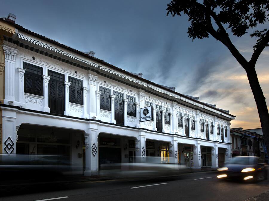 Um edifício histórico com fachada branca, várias janelas e uma placa com a inscrição 'VENUE'.