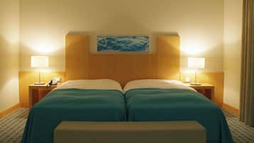Uma cama de casal com cabeceira, duas luminárias de apoio, um telefone e um quadro sobre a cama.