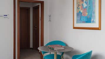 Um quarto com uma pequena mesa redonda, duas cadeiras turquesa e um quadro pendurado na parede.