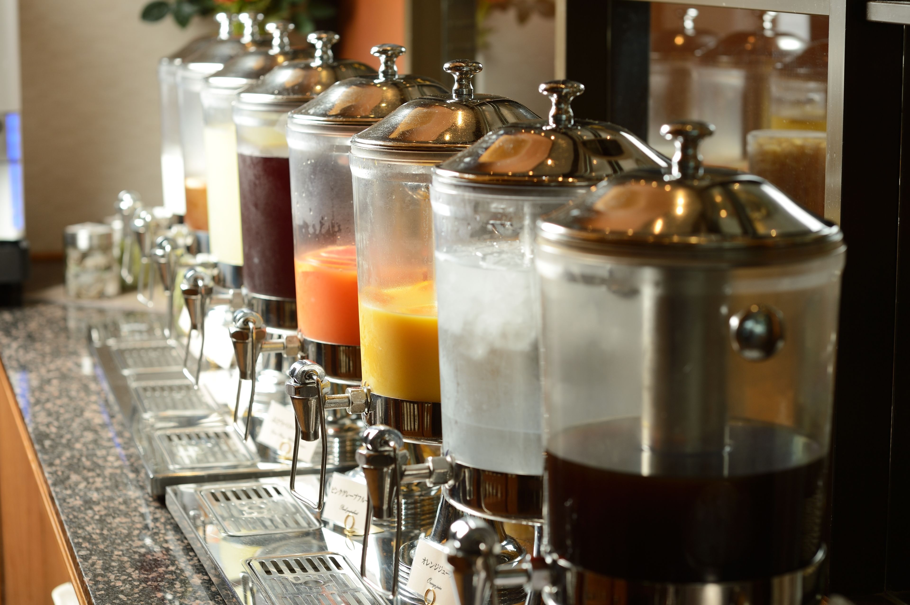 Estação de distribuição de bebidas com várias opções, incluindo sumos e café.