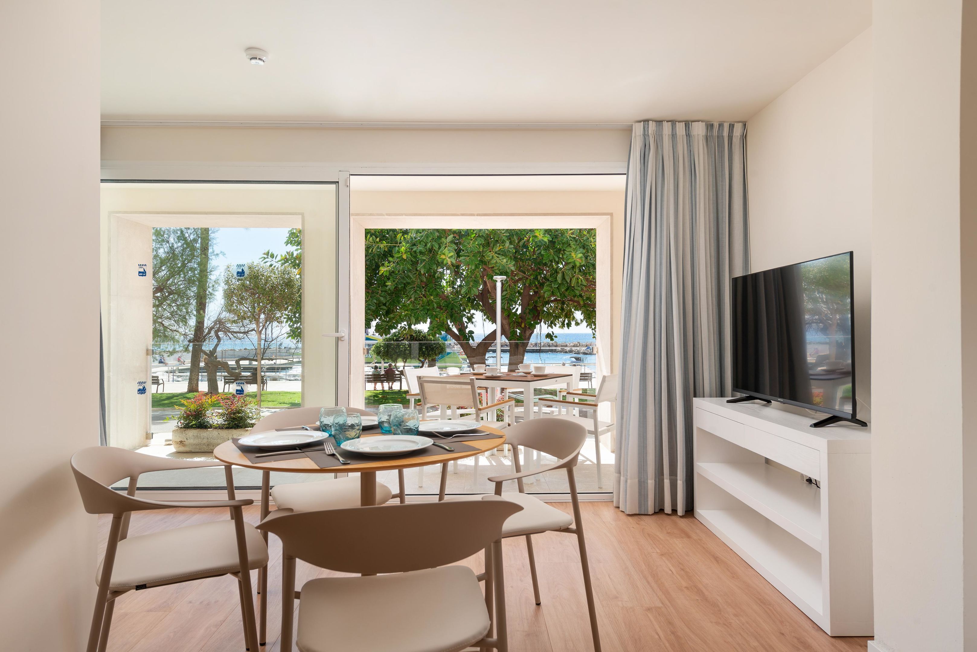 Sala de estar moderna com área de jantar, TV de tela plana e vista para o exterior.