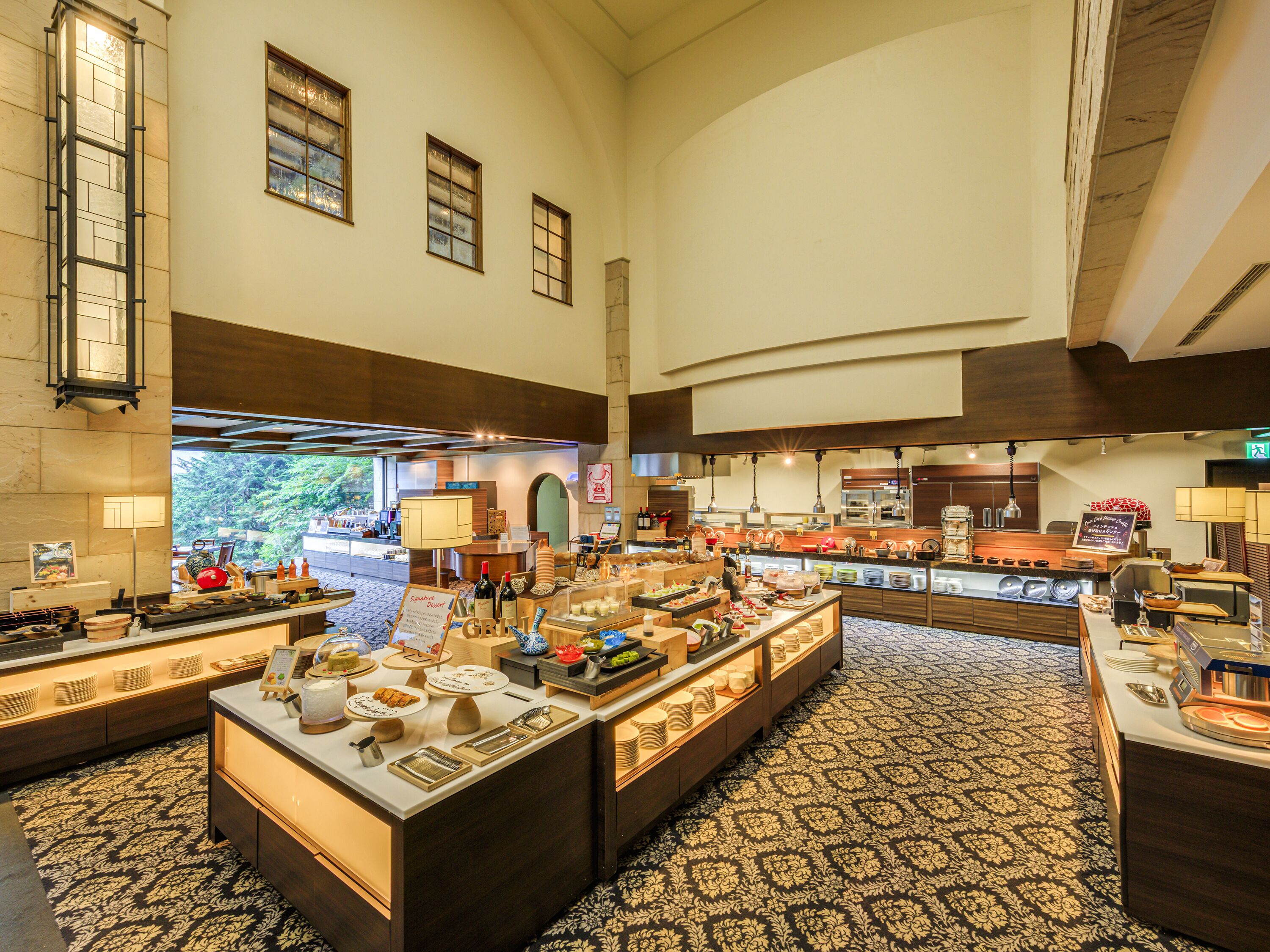 Espaço de buffet com diversas estações de comida e vista para o exterior.