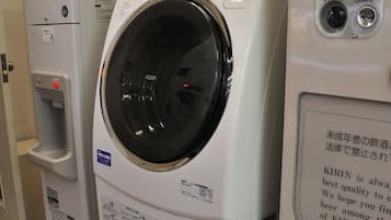 Máquina de lavar com abertura frontal, painel de controle frontal, dispensador de água e etiqueta com texto em japonês.