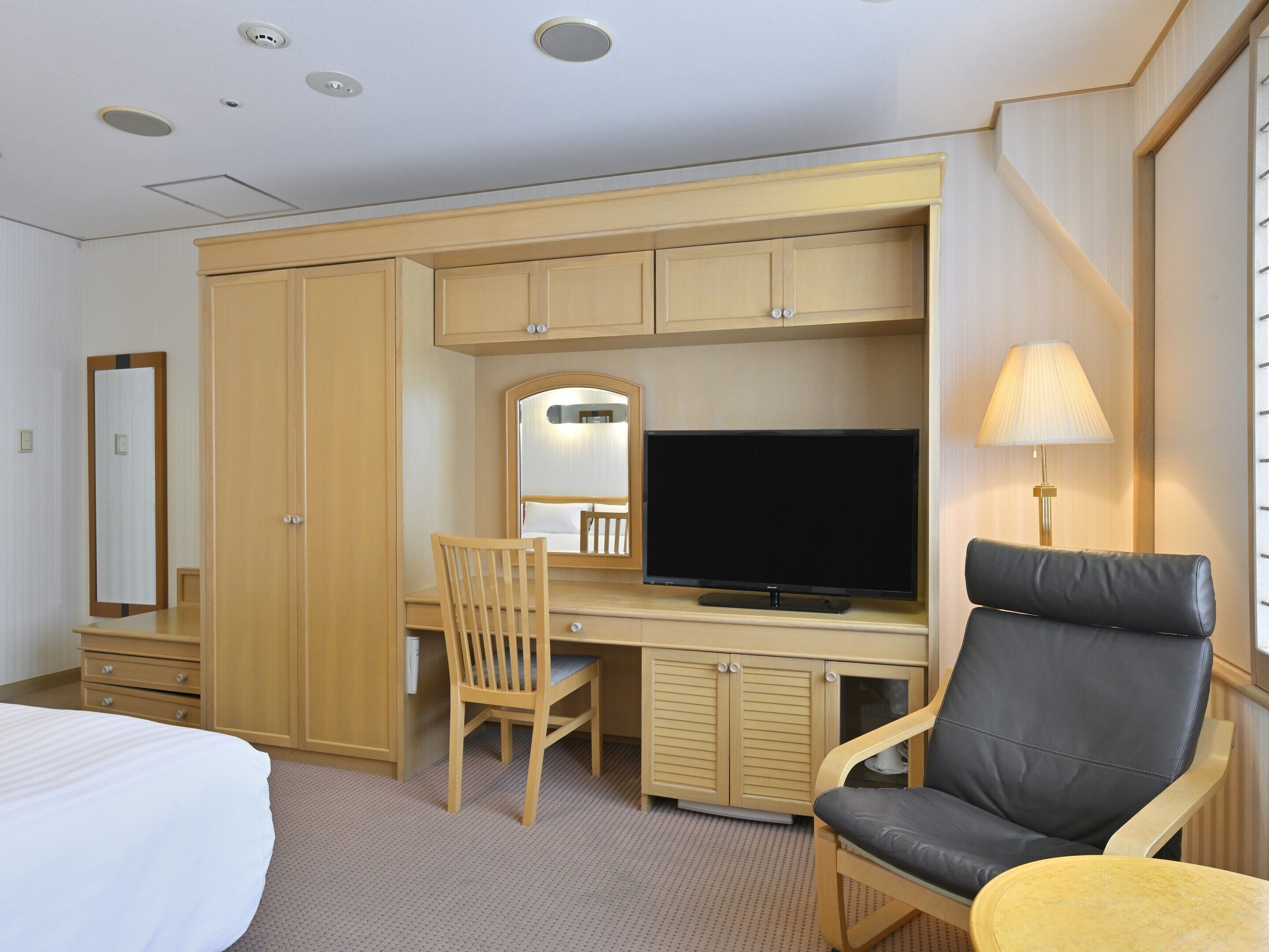 Quarto de hotel com uma cama, uma mesa de escritório com televisão, uma cadeira e um abajur.