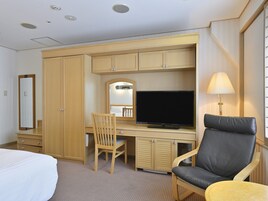 Quarto de hotel com uma cama, uma mesa de escritório com televisão, uma cadeira e um abajur.