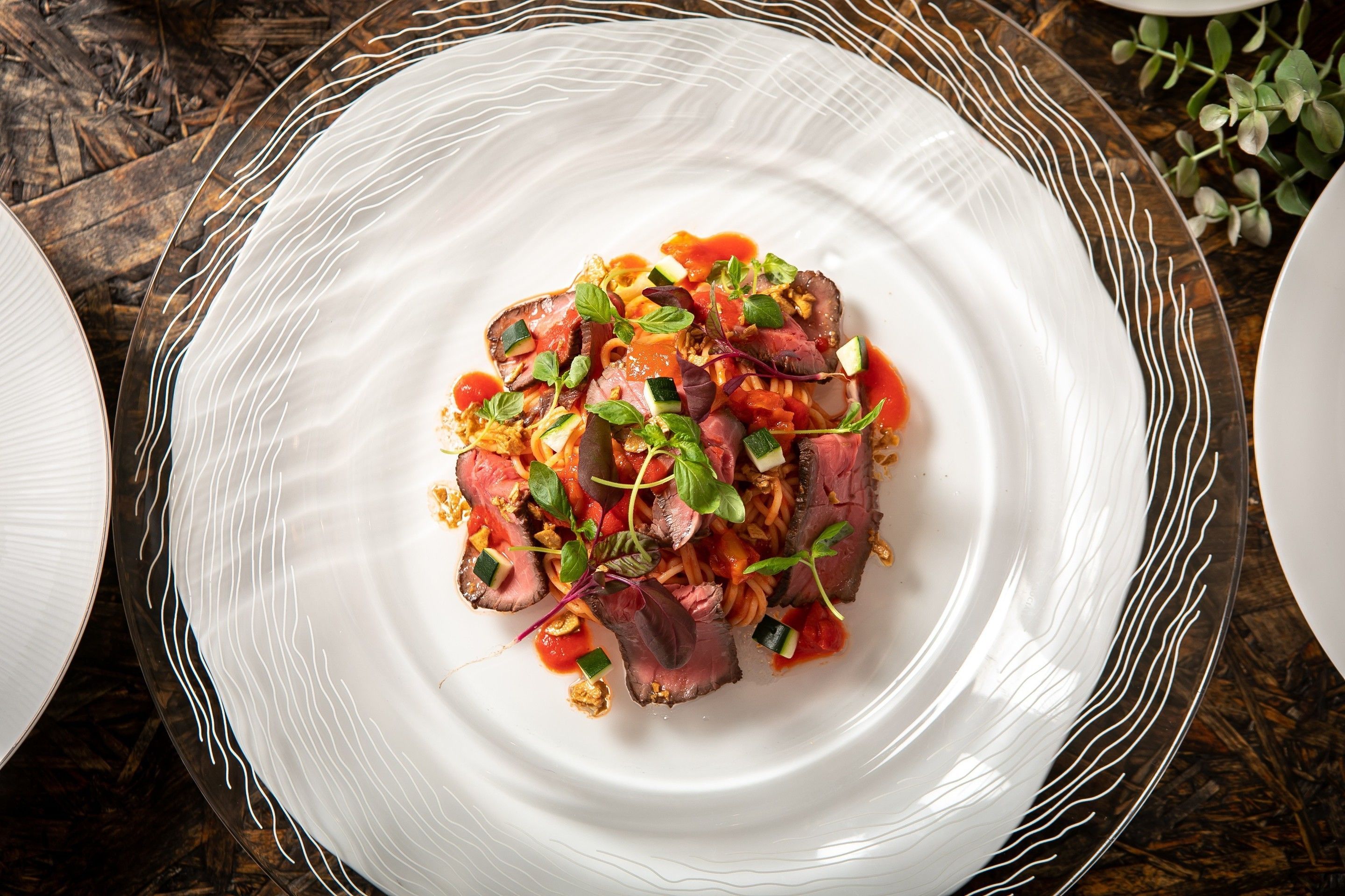 Um prato branco com bife e legumes sobre uma mesa de madeira.