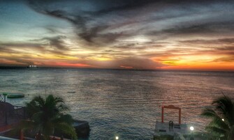 Um pôr do sol sobre a água, com um navio ao longe e um pequeno cais com um ressalvador.