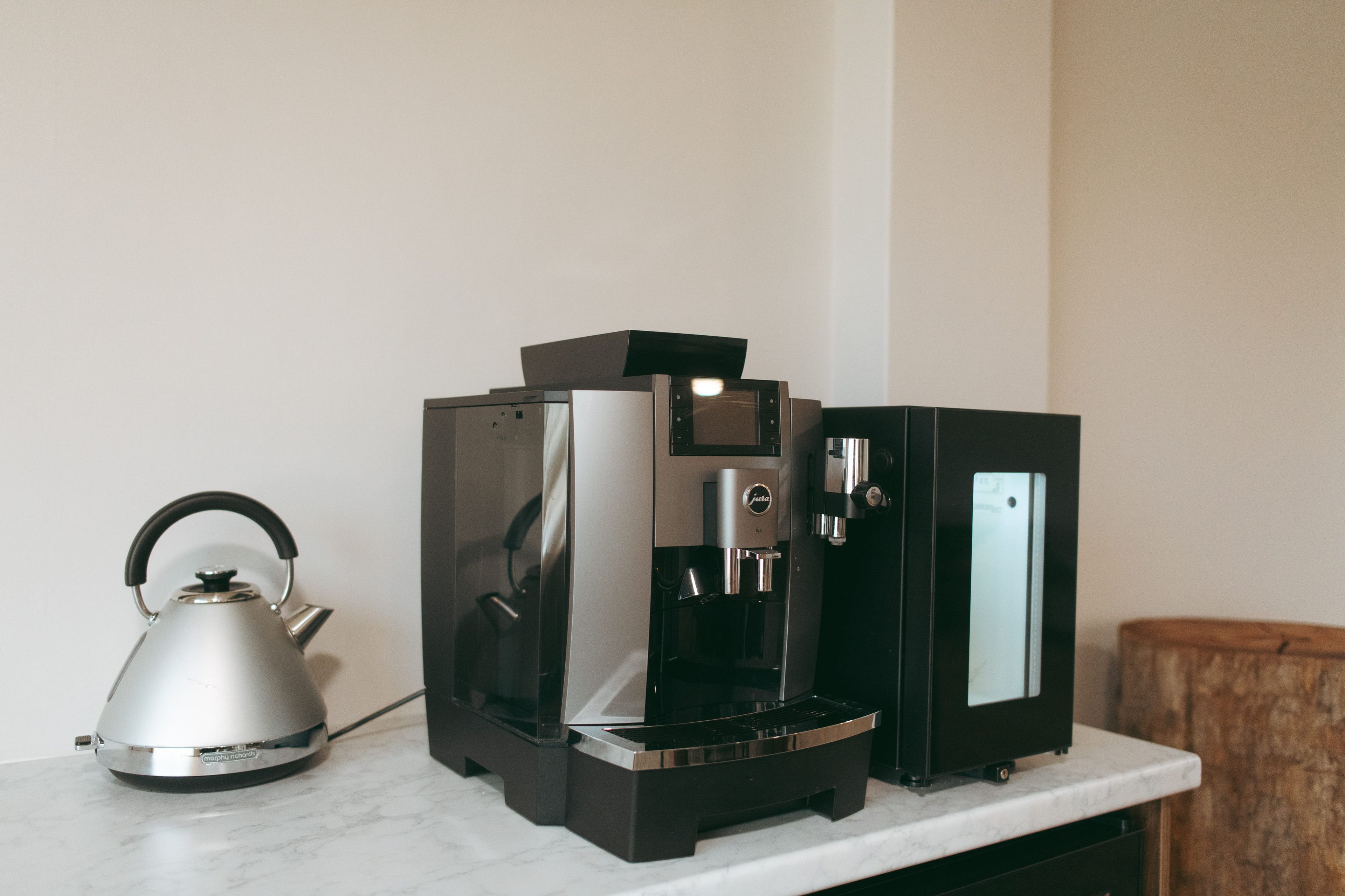 Máquina de café e chaleira em bancada de mármore.