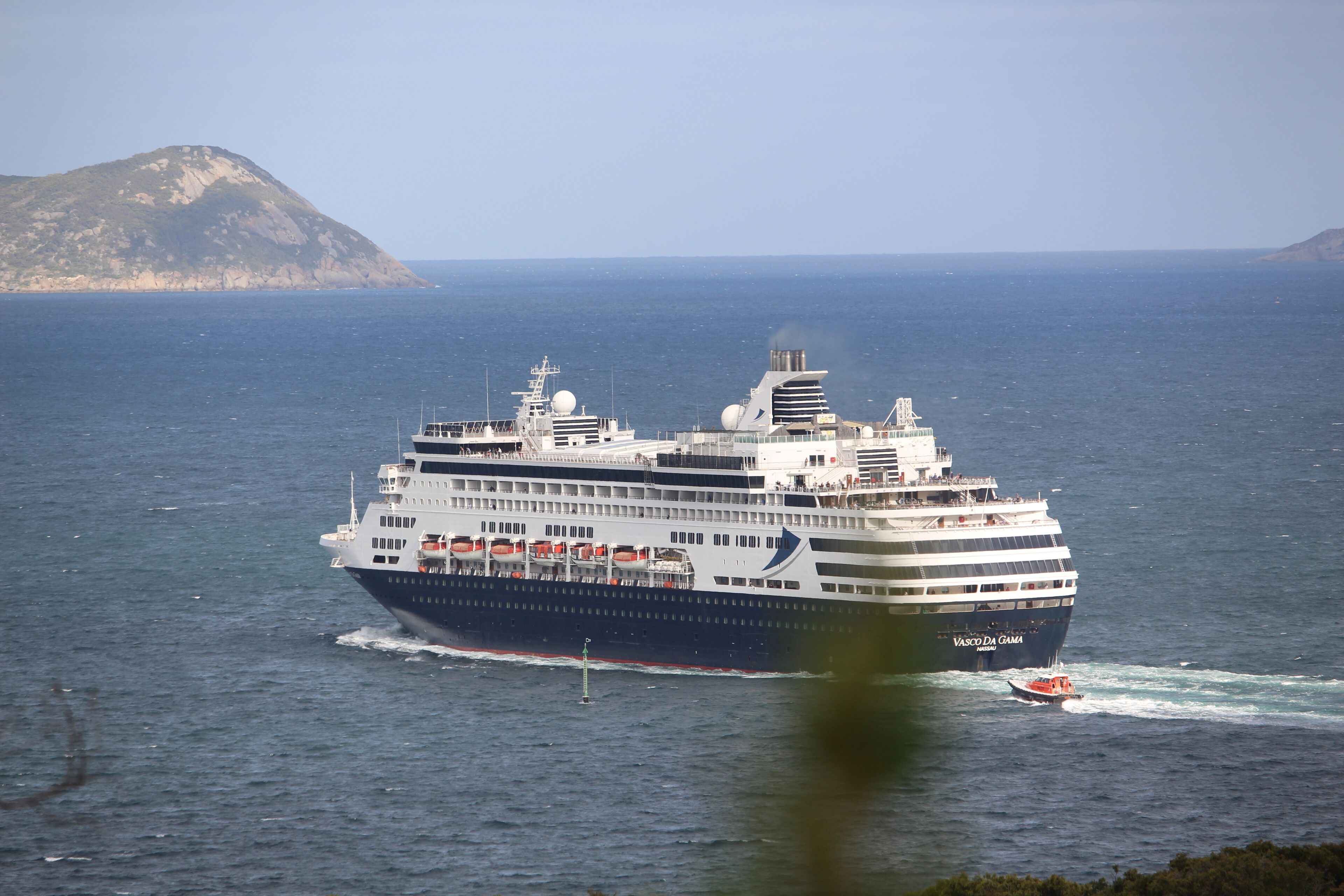 Um grande navio de cruzeiro com vários decks e um bote salva-vidas visível.