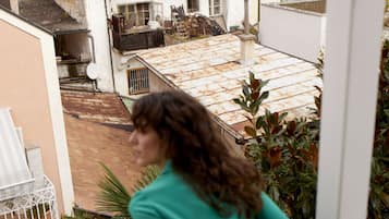 Varanda com vista para um pátio, com guarda-corpo branco e plantas em vasos.