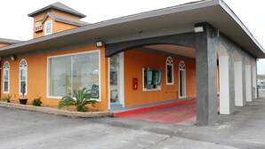 Um motel com toldo vermelho, uma grande janela e uma placa que diz 'Motel'.