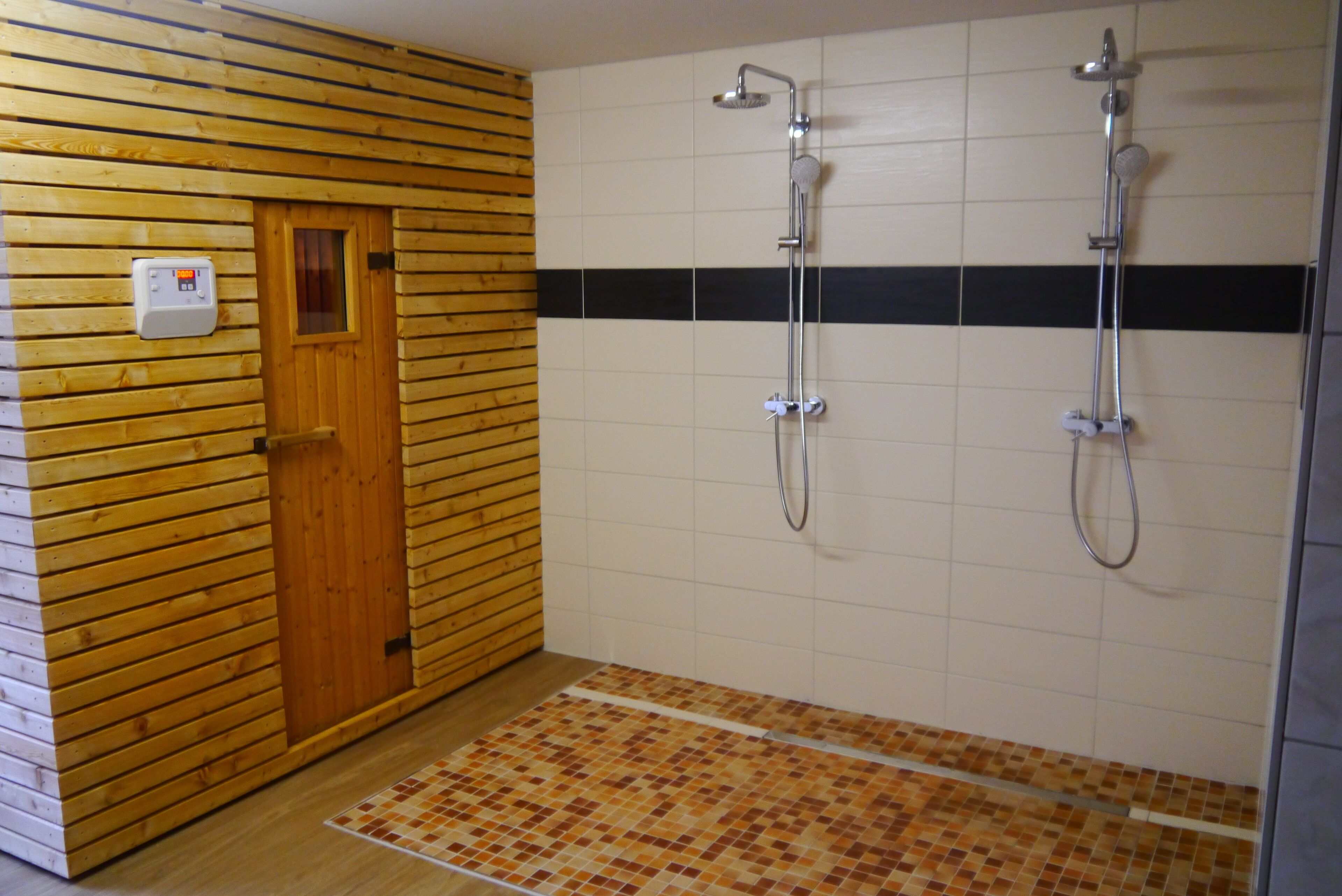 Casa de banho com painéis de madeira, chuveiro com painel de comando e chão em azulejos.