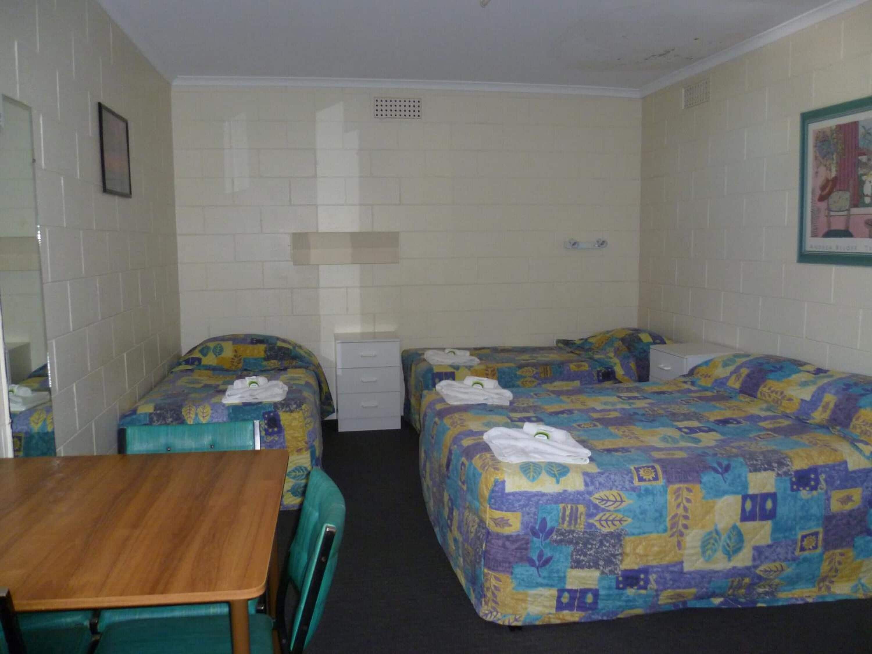 Quarto com duas camas, uma mesinha e uma cadeira.