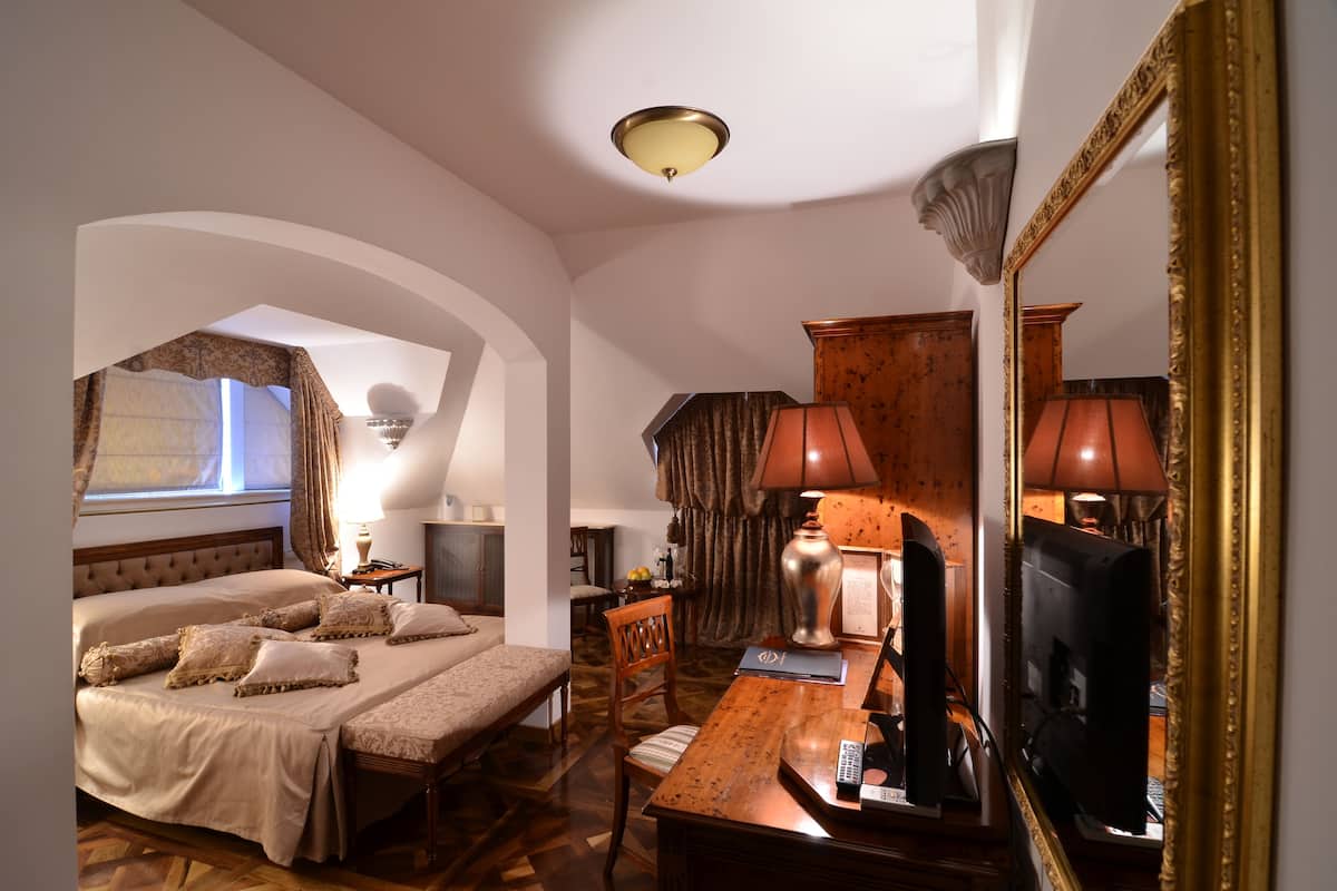 Quarto de hotel com uma cama grande, uma escrivaninha com um computador, uma televisão e um espelho.