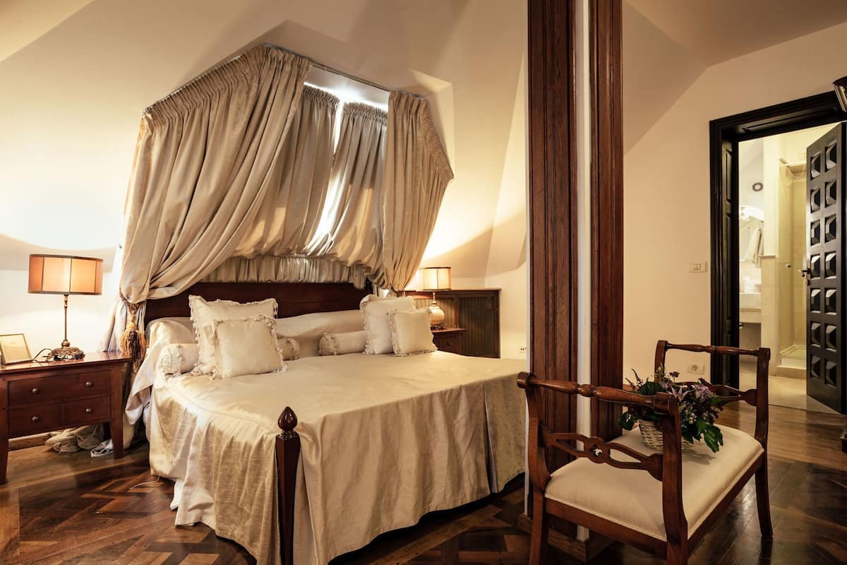 Quarto com cama de dossel, móveis de madeira e uma cadeira com planta.