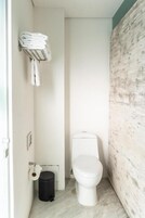Um banheiro pequeno e branco, com vaso sanitário, porta-toalhas e lixeira.