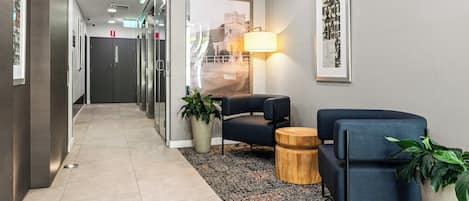 Um lobby moderno com área de estar, uma luminária e um quadro na parede.