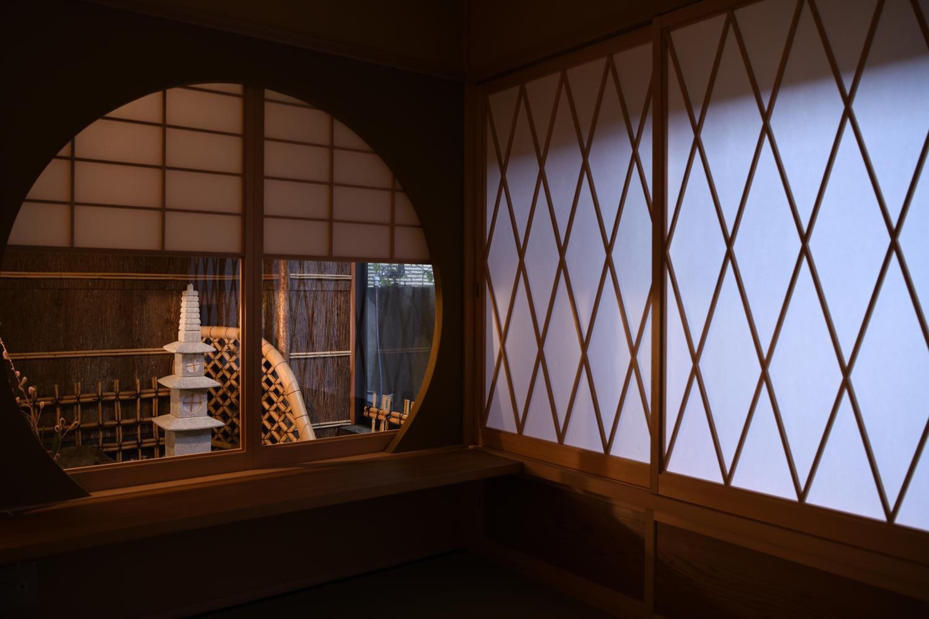 Um quarto japonês tradicional com piso de esteira de tatame, um painel shoji e vista para uma pagoda através da janela.