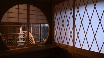 Um quarto japonês tradicional com piso de esteira de tatame, um painel shoji e vista para uma pagoda através da janela.