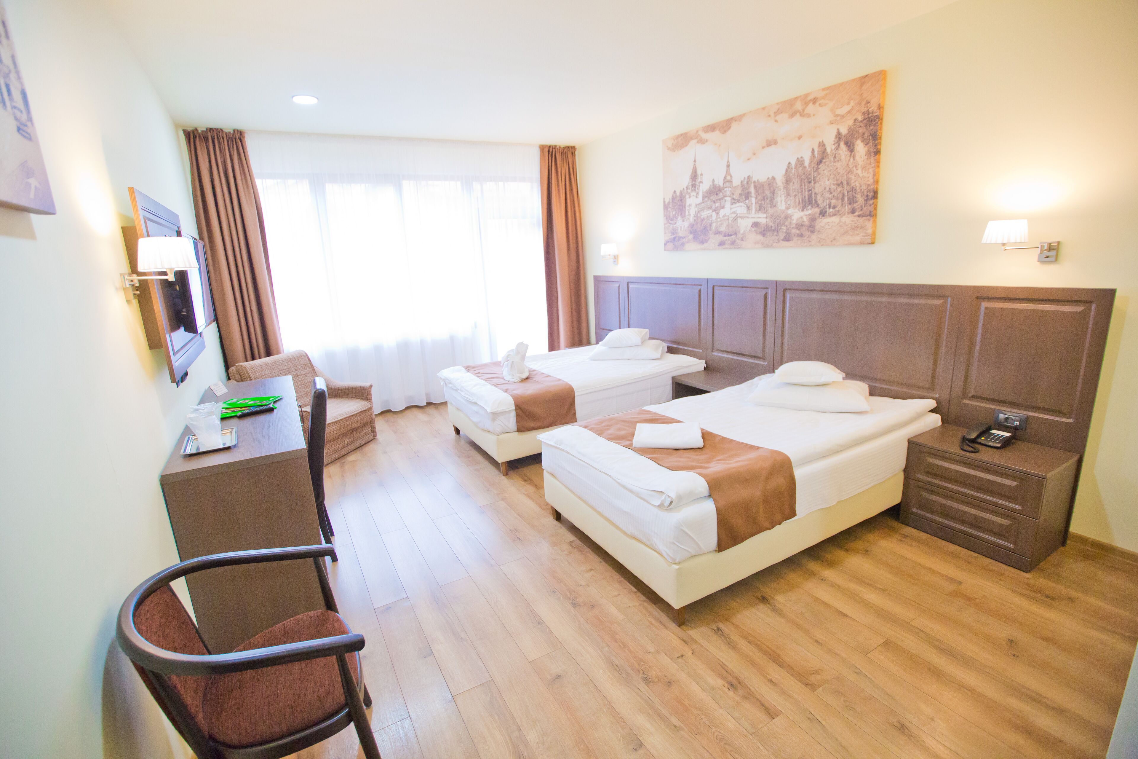 Quarto de hotel com duas camas, uma escrivaninha e uma cadeira.