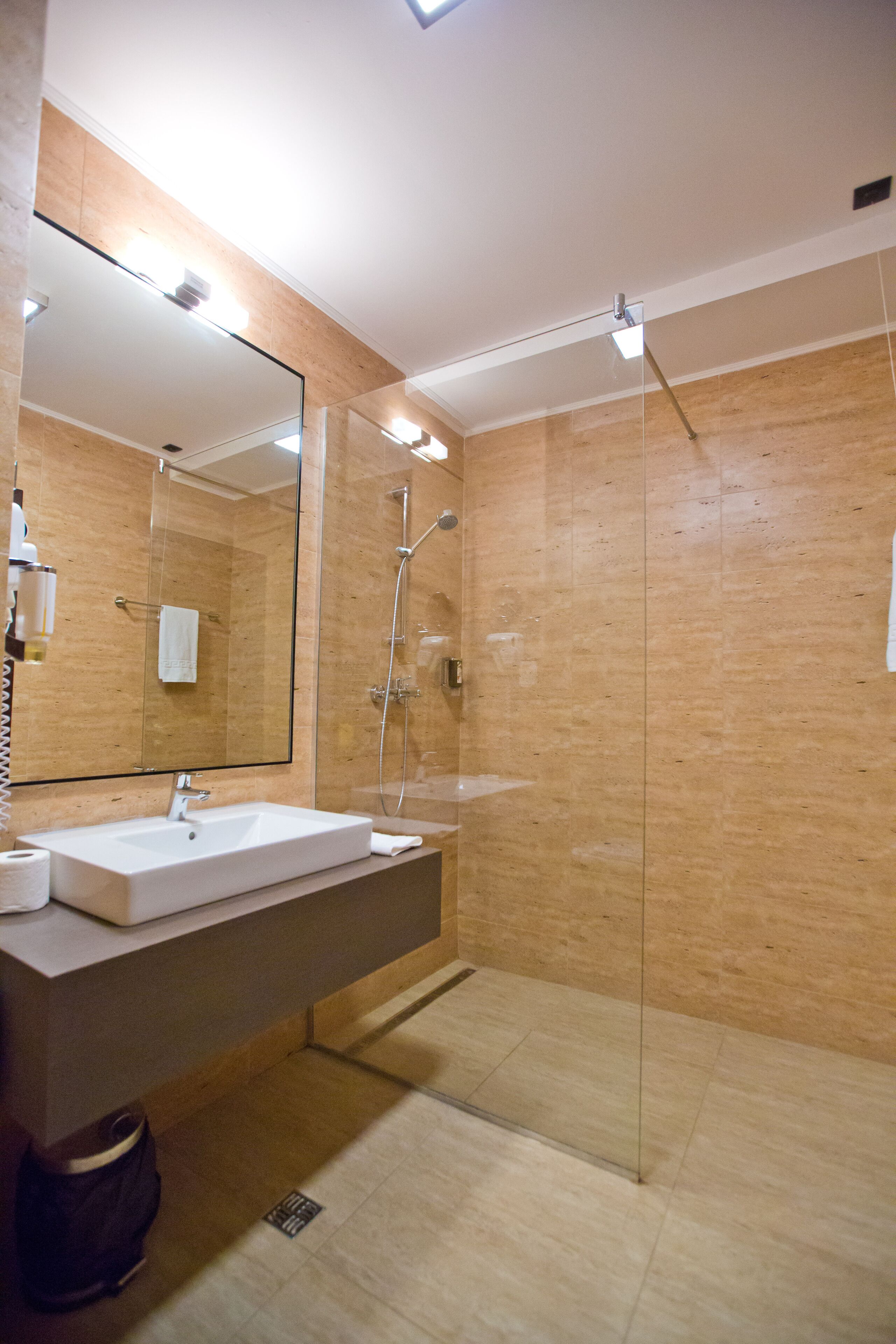 Casa de banho moderna com um espelho grande, lavatório e cabine de duche em vidro.