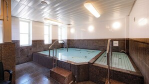 Piscina com degraus de acesso, rodeada por paredes de pedra e piso cerâmico.