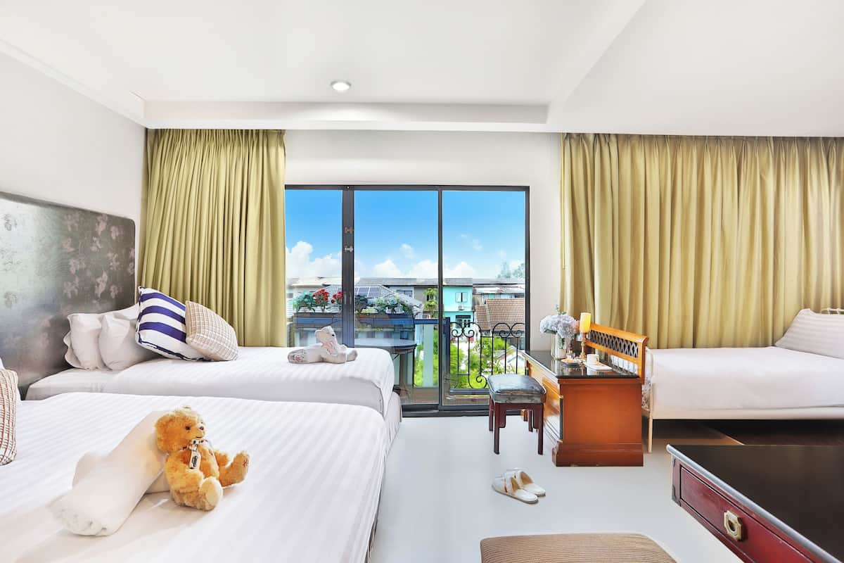 Quarto de hotel com duas camas, varanda com vista, uma pequena mesa e uma cadeira.