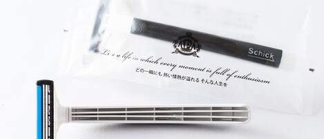 Uma navalha, uma lâmina de navalha Schick e uma embalagem com texto em japonês.