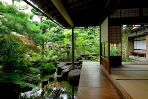 Um jardim japonês tradicional com lago de carpas, passarelas de madeira e vegetação exuberante.