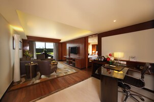Quarto de hotel moderno com área de estar, espaço para refeições e cozinha.