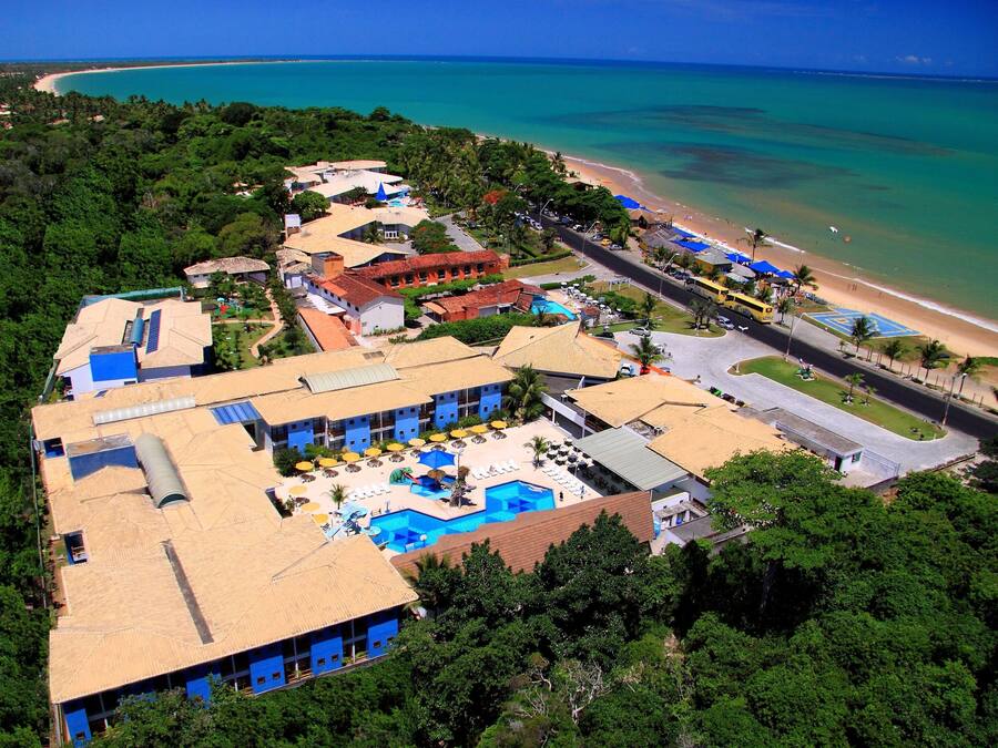 Vista aérea de um resort com vários edifícios, uma piscina e uma praia.
