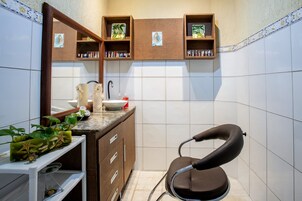 Um banheiro com pia, espelho, prateleiras com produtos de higiene e um vaso de planta.