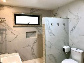 Uma casa de banho moderna com chuveiro, sanita e lavatório.
