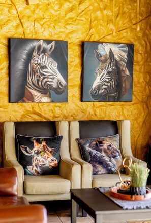 Quarto com duas poltronas, cada uma com uma almofada com tema de zebra, e uma mesa com um objeto decorativo.