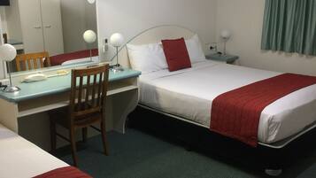 Quarto de hotel com duas camas, uma escrivaninha, uma cadeira, um espelho e um ar condicionado.
