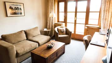 Uma sala de estar acolhedora com um sofá, uma mesa de centro de madeira, uma poltrona e uma escrivaninha.