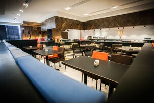 Um restaurante moderno com um balcão comprido, várias mesas e cabines.