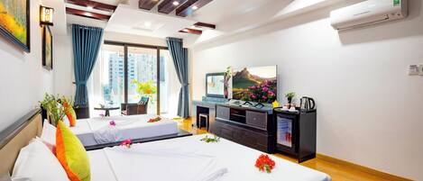 Quarto de hotel com duas camas, uma escrivaninha, uma TV e vista para a cidade.