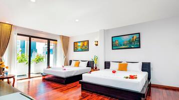 Quarto de hotel com duas camas, uma janela grande com cortinas, um quadro na parede e vista para prédios lá fora.