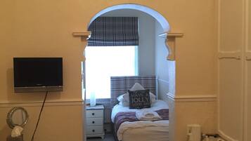 Quarto de hotel com cama, televisão, escrivaninha e cadeira.