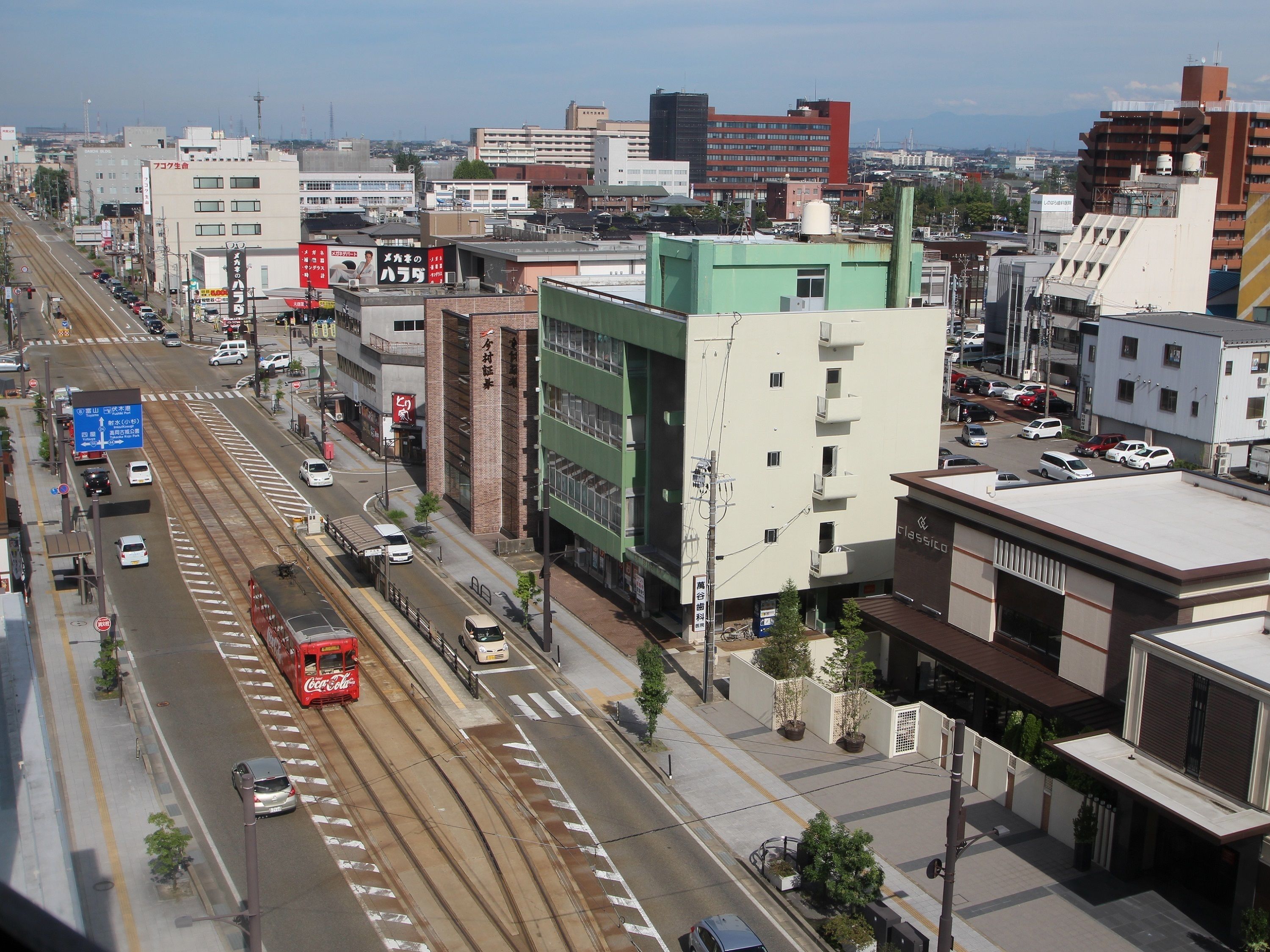 Paisagem urbana com linha de eléctrico, edifícios e um camião Coca-Cola.