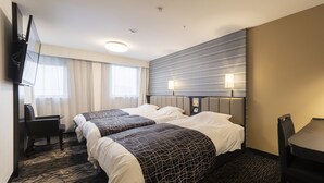 Quarto de hotel com duas camas, uma escrivaninha, uma cadeira e uma televisão.