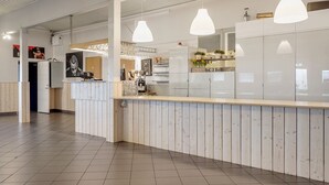 Cozinha moderna com armários brancos, bancada de madeira e iluminação pendente.