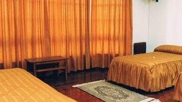 Quarto com duas camas, uma mesa pequena, um abajur e um quadro na parede.