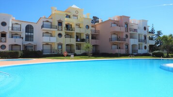 Um hotel com vários andares, varandas, piscina e céu claro.