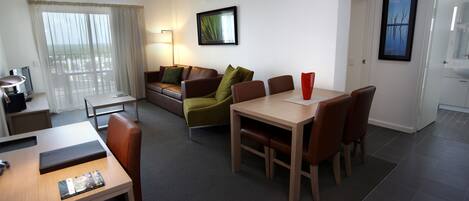 Uma sala de estar moderna com área de jantar, sofá, mesa de centro e televisão.
