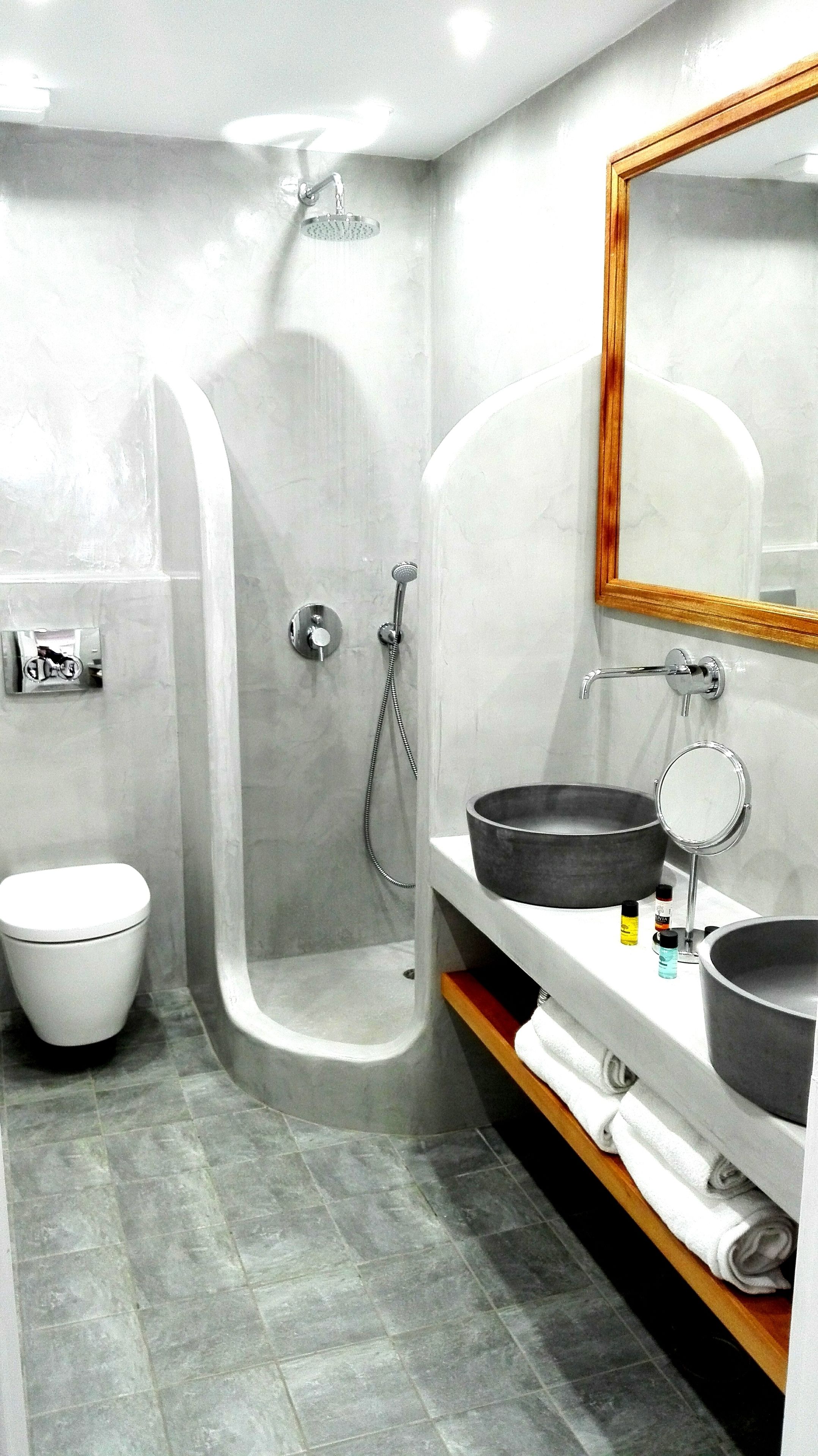 Uma casa de banho moderna com chuveiro, sanita e zona de lavatório.