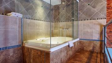Casa de banho com jacuzzi em vidro, paredes em azulejo e parede decorativa em tijolo.