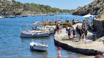 Uma marina costeira com barcos atracados e pessoas caminhando pelo cais.