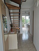 Uma cozinha moderna com escada de madeira, área de jantar com cadeiras e vista para o exterior.